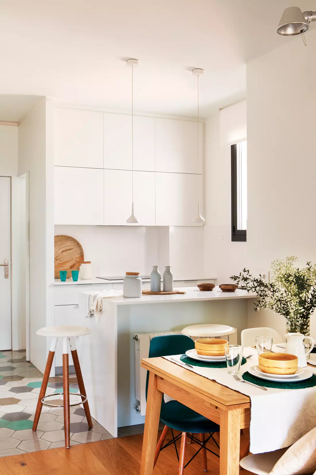 Small kitchen and office with wooden table and green and white chairs