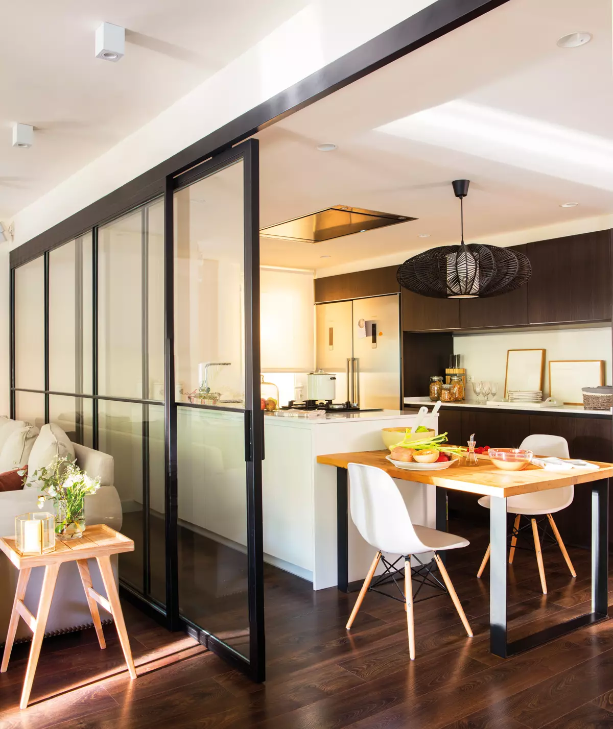 Kitchen with glass wall and black enclosure and office with a table attached to the island