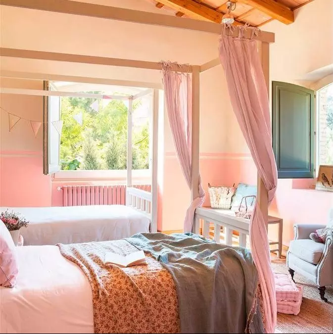 Chambre rose pastel avec plafond en bois, lit à baldaquin et rideaux roses, banderoles décoratives et plaid