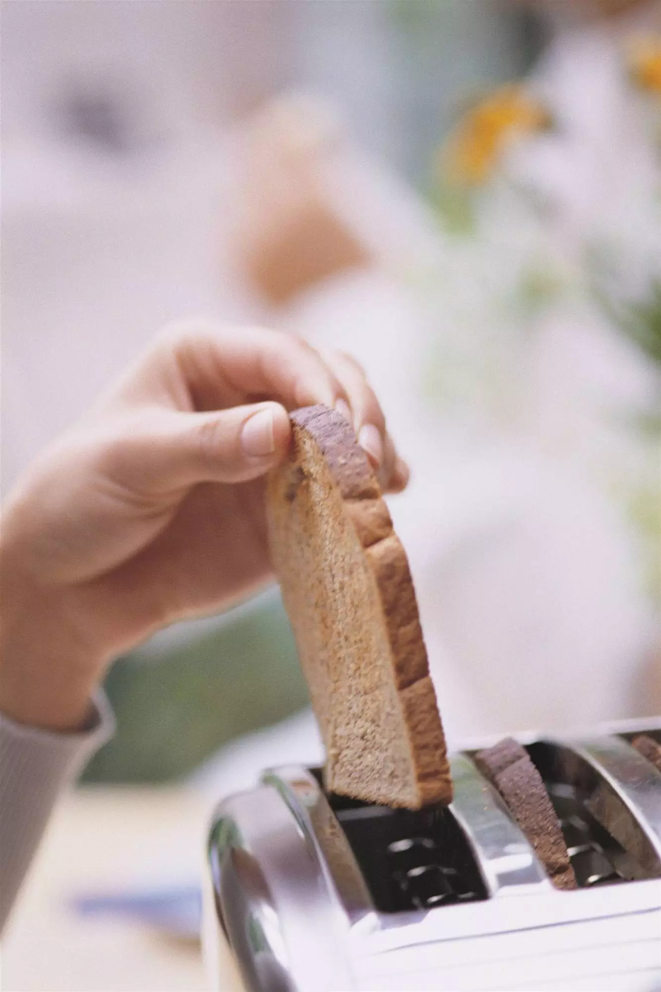 Hande wat roosterbrood uit die broodrooster haal