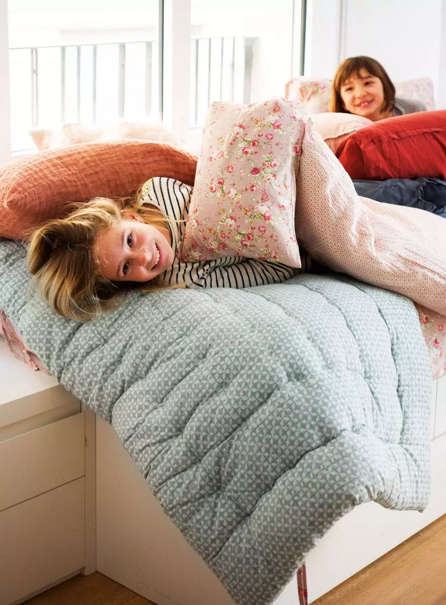 girls-playing-on-bed-with-duvets-and-cushions-in-childrens-room-451595