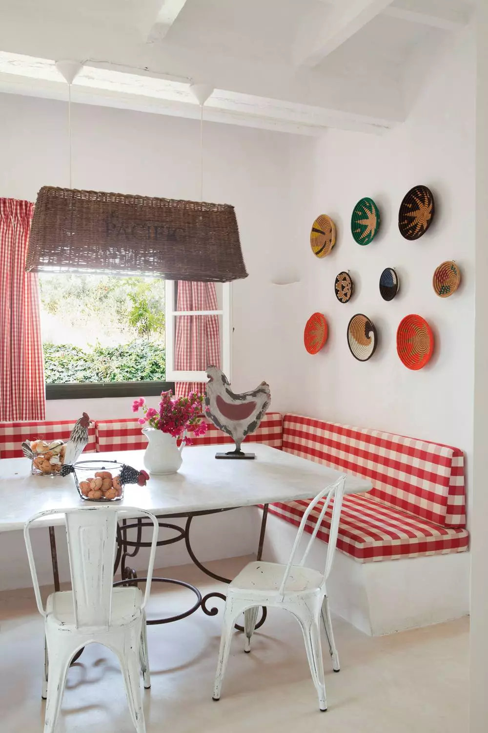 Salle à manger blanche avec détails rouges et composition d'assiettes au mur