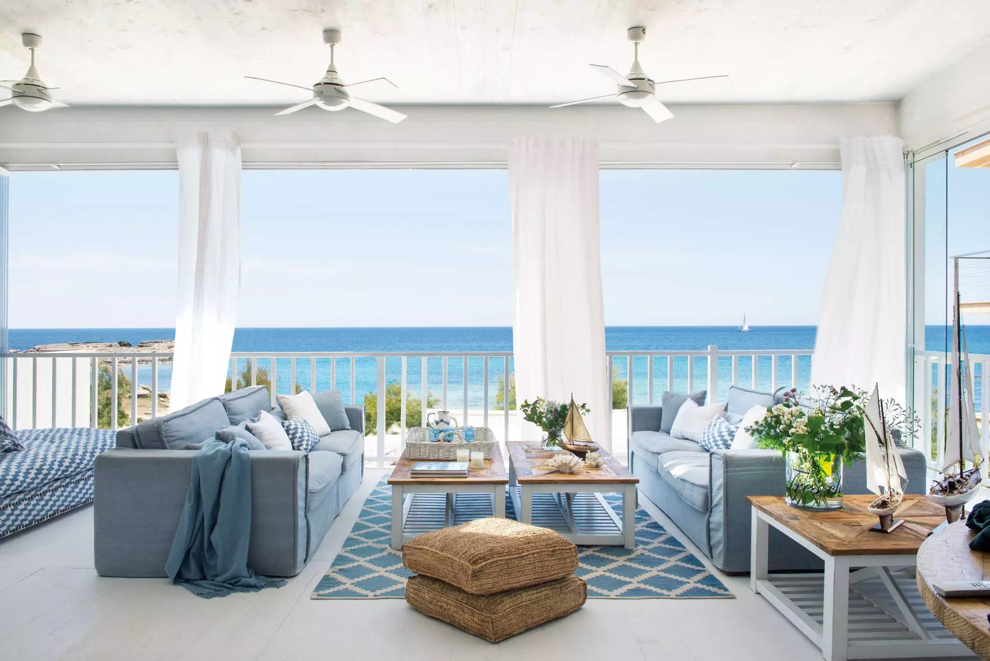 summer-living-room-with-blue-sofas-and-ceileing-fans-and-looking-to-the-sea 461865